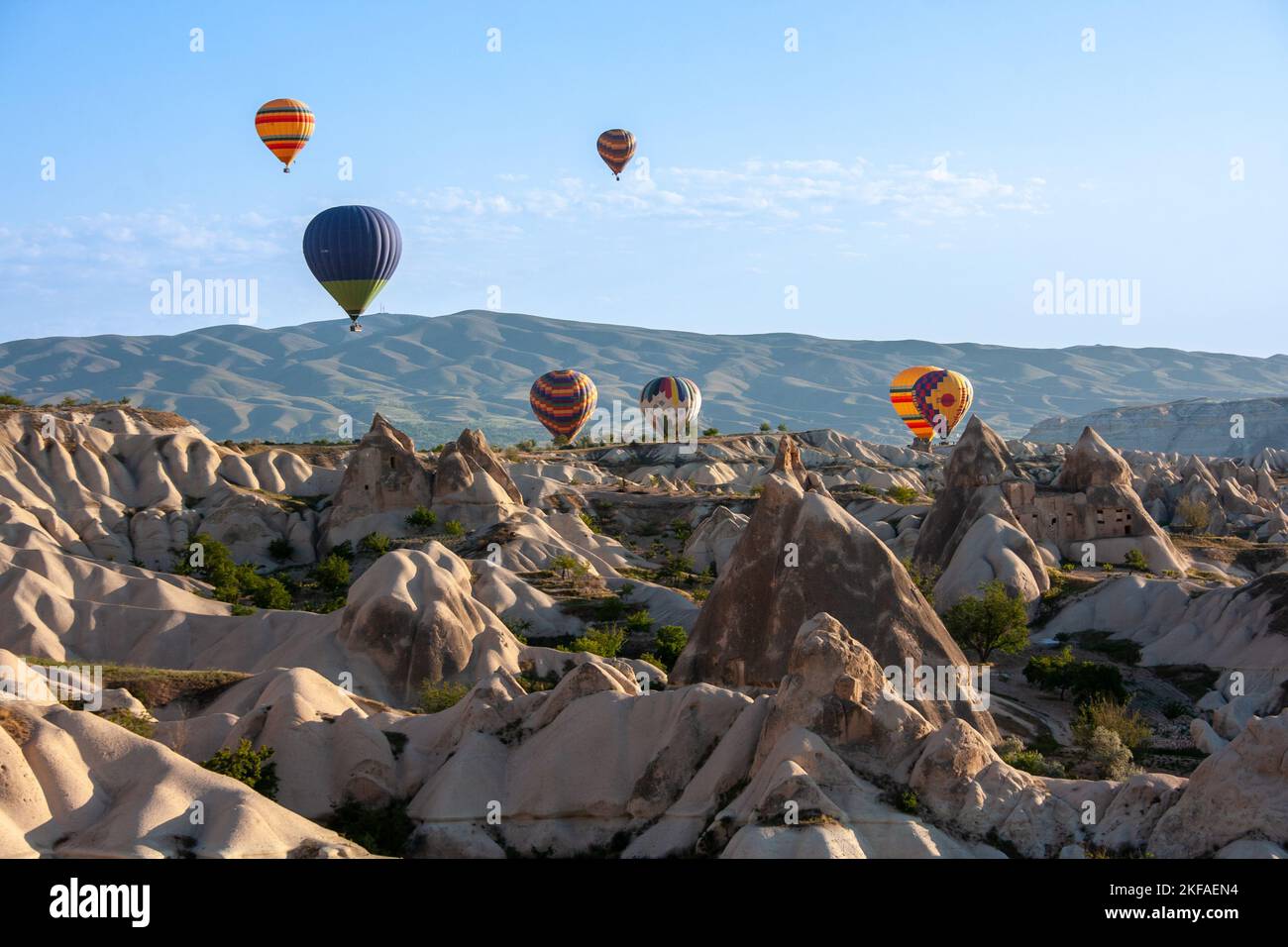 hot air balloons rise over the chimneys rock formation, Cappadocia ...