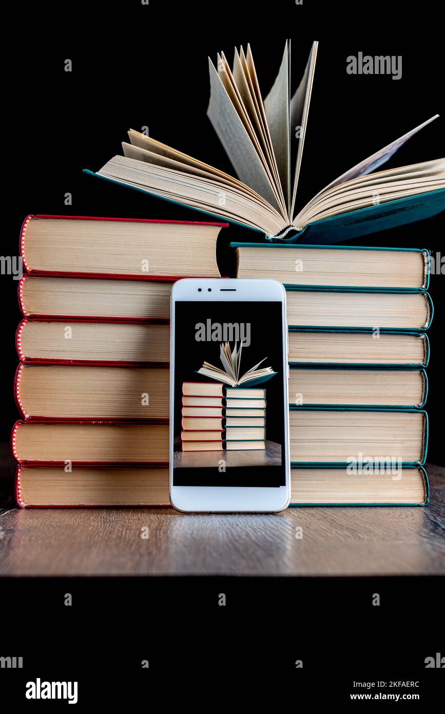 Stack of books with an open book and a smartphone. On the smartphone ...