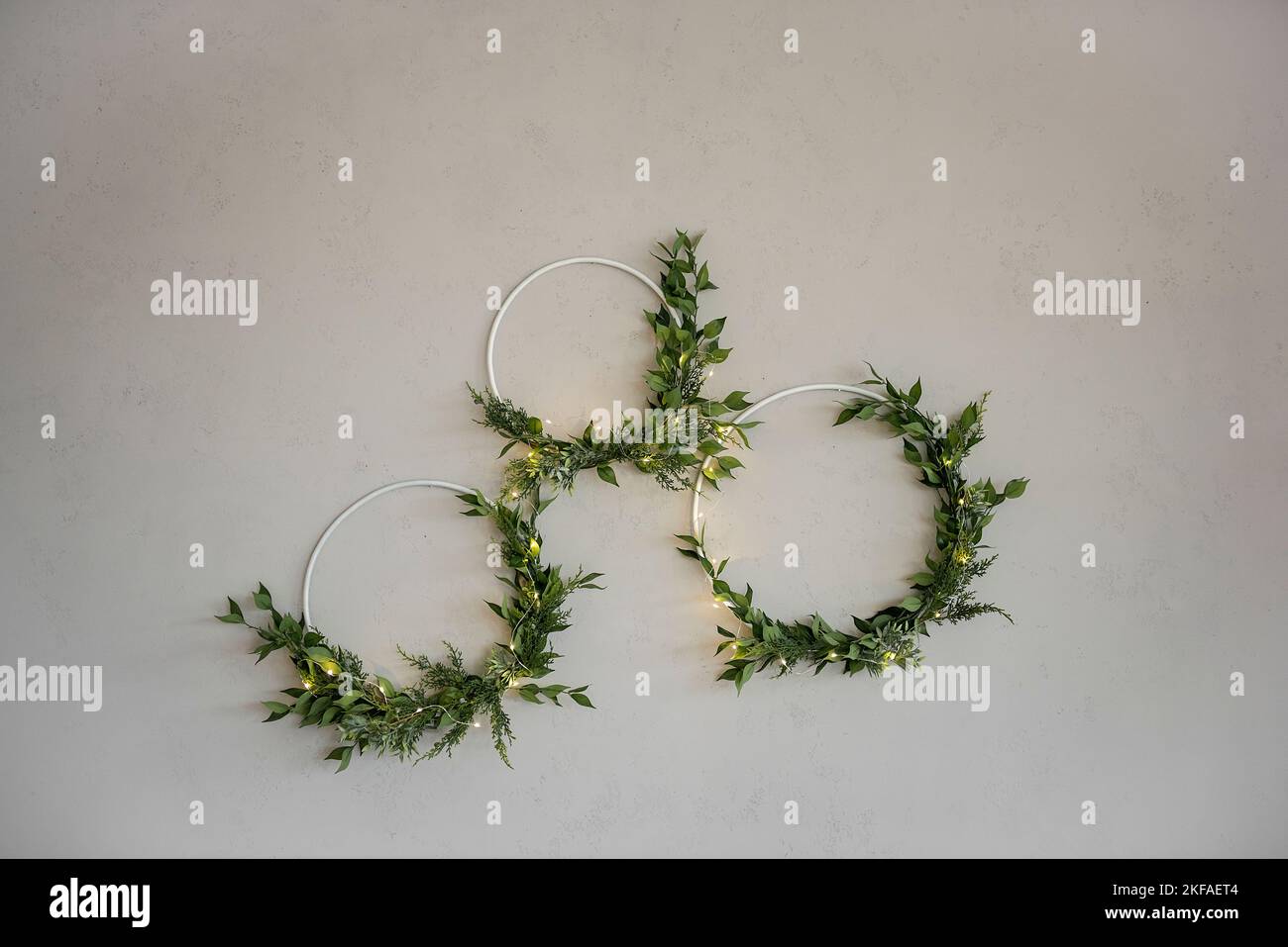 On gray concrete wall, there are three laconic, elegant, green wreaths ...
