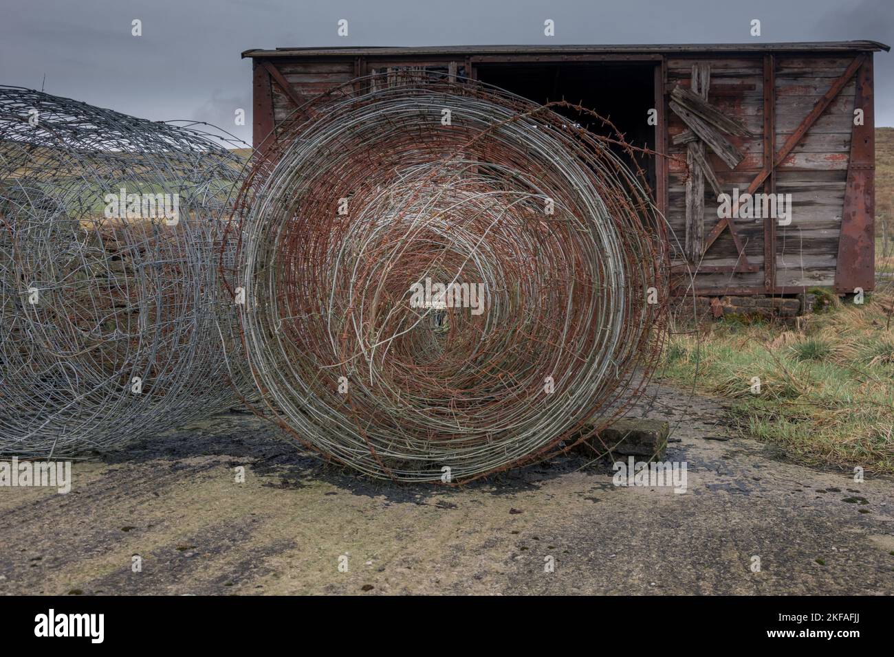 Old role of metal fencing wire, rusting on the floor with old derelict ...