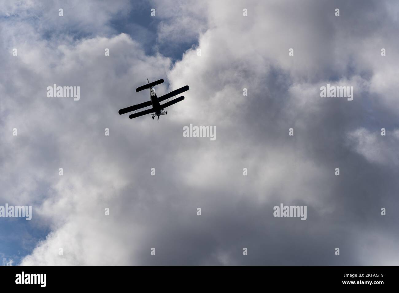 A low-angle shot of an airplane with aircraft trail against the cloudy ...