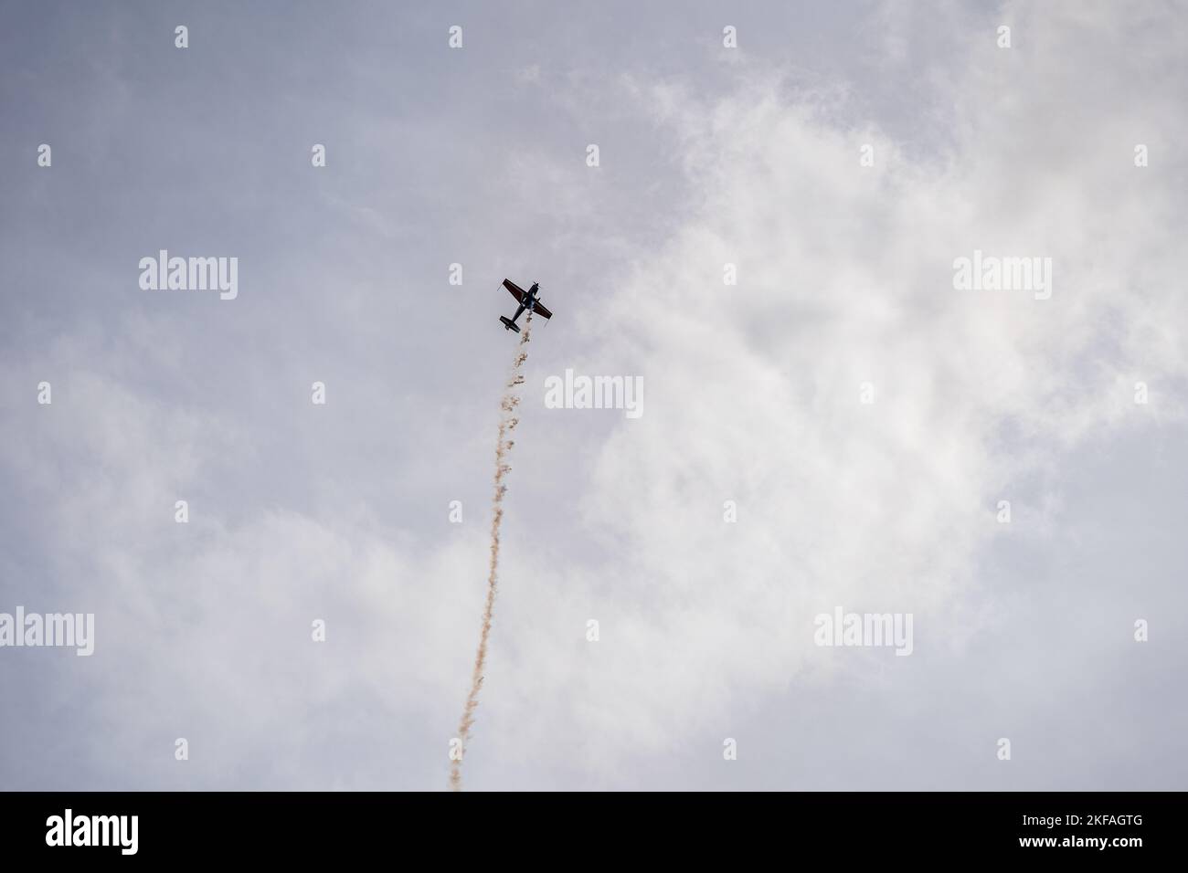 A low-angle shot of an airplane with aircraft trail against the cloudy ...