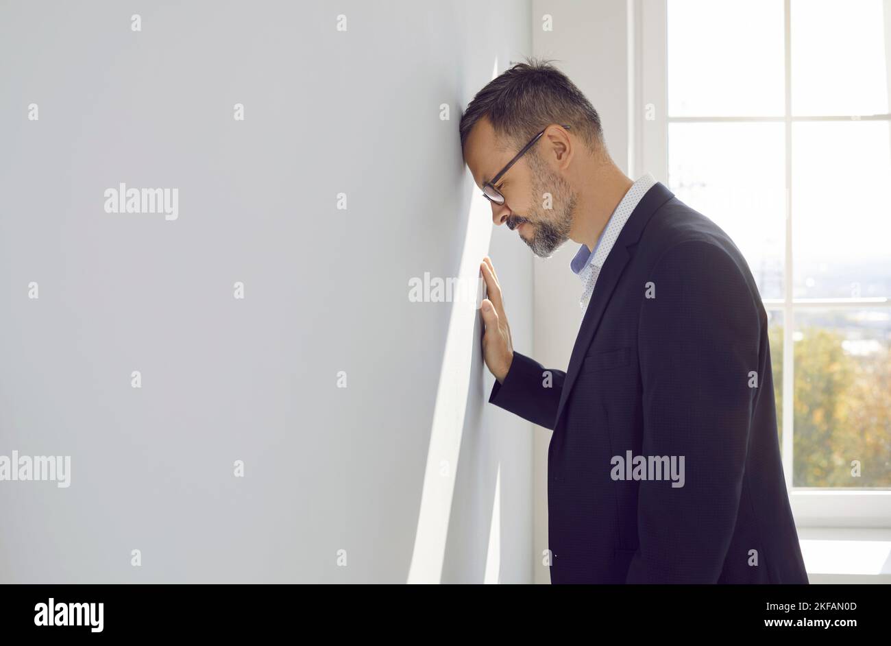 Businessman gets tired of problems, feels frustrated and bangs his head ...