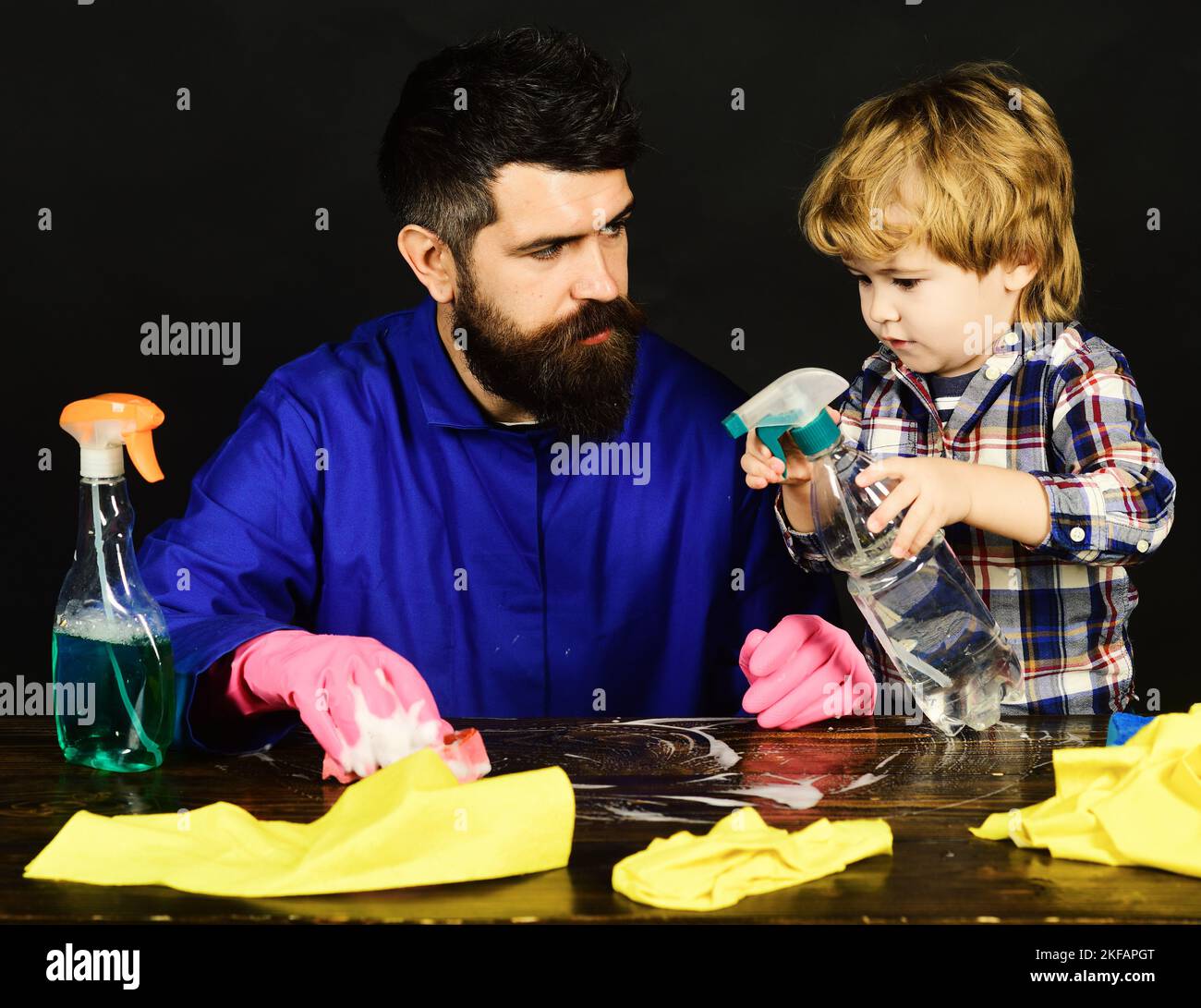 Man with cute child on black. Kid and father with busy faces cleaning ...