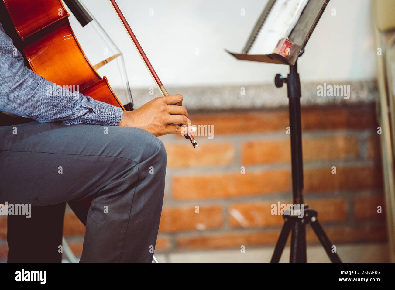 A musician playing cello with musical notes on the book notation stand ...