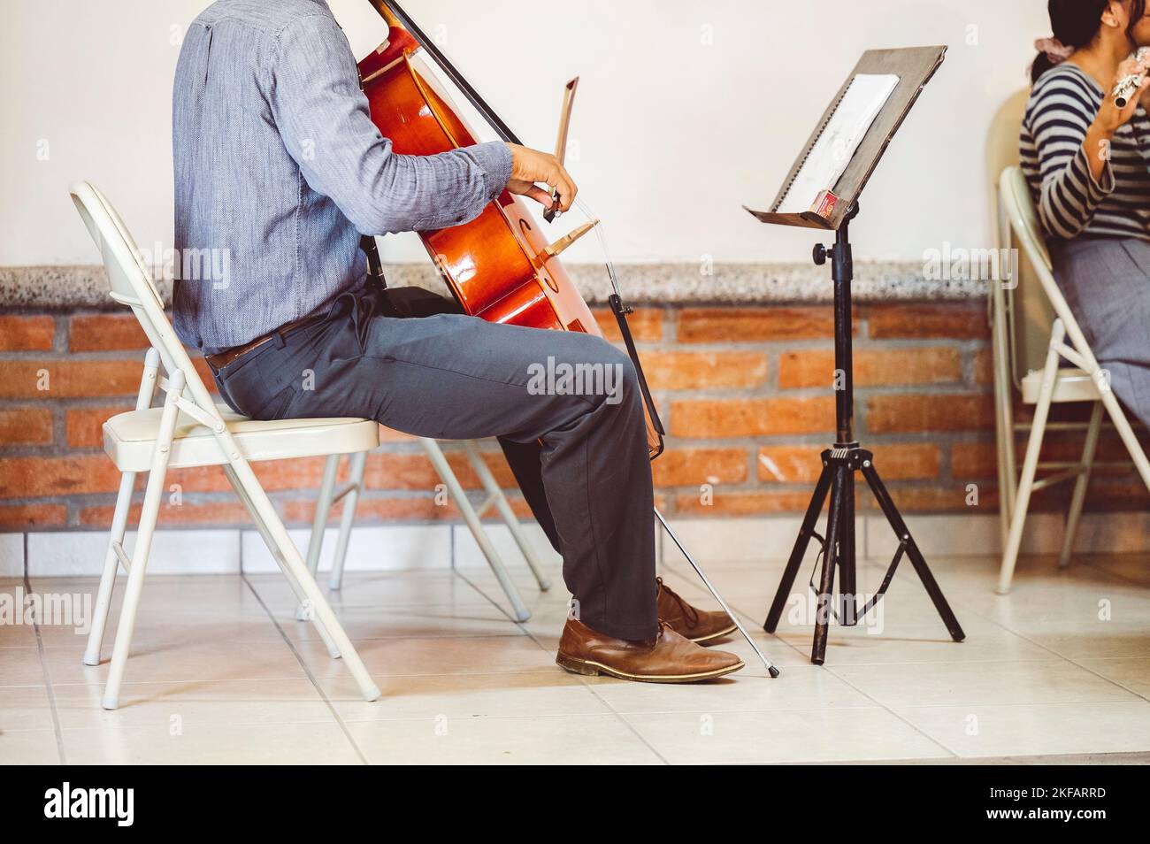 A musician playing cello with musical notes on the book notation stand ...