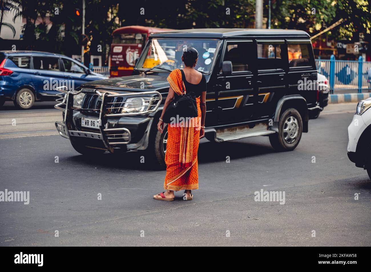 A woman wearing traditional Indian clothing and crossing the road with ...