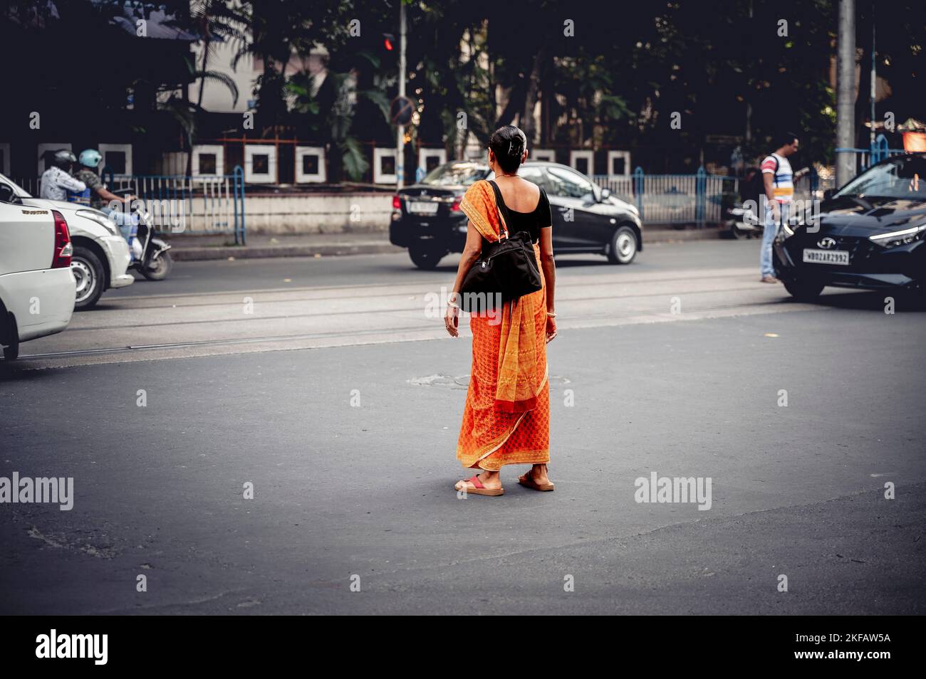 A woman wearing traditional Indian clothing and crossing the road with ...