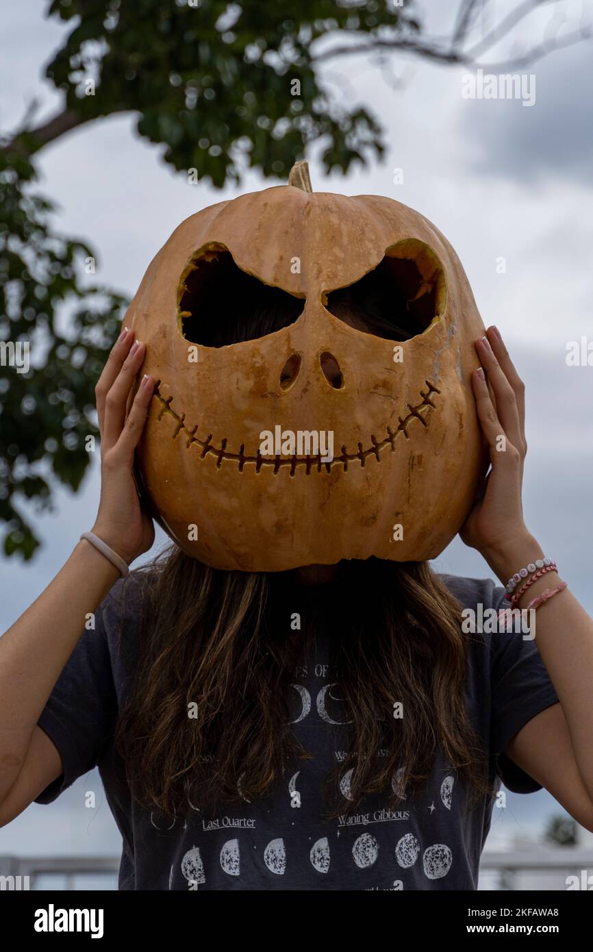 young woman with pumpkin head after cutting it off and putting a face ...