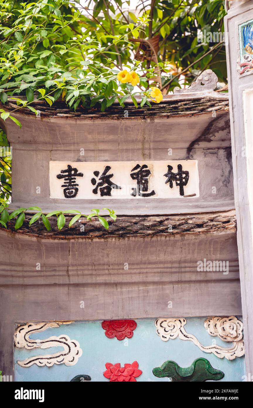 A vertical shot of a wall with writings on it seen at a Buddhist temple ...