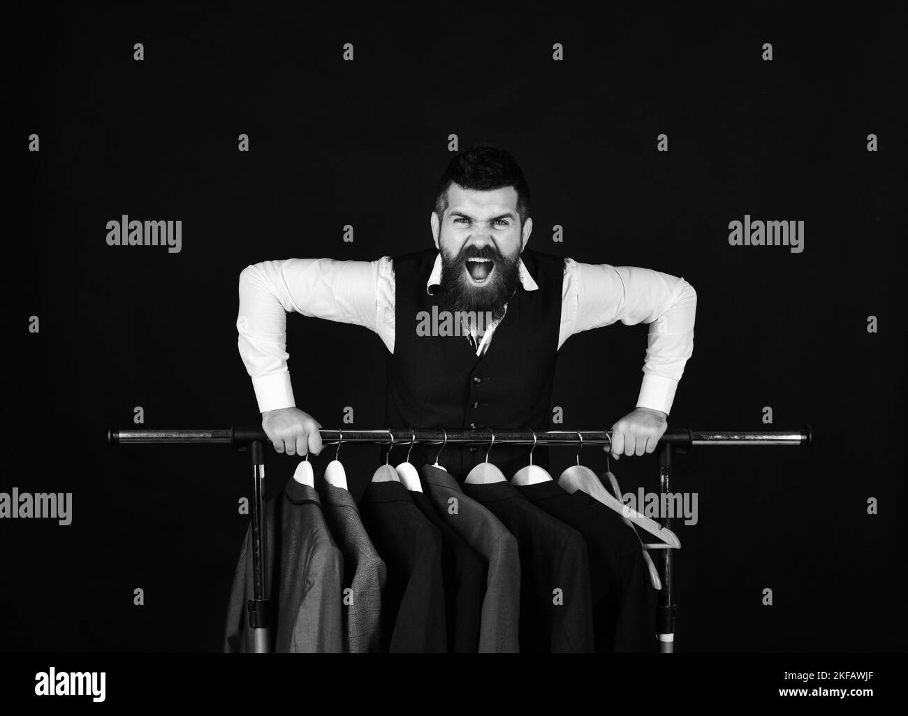 Tailor with angry face near custom jackets on black background Stock ...