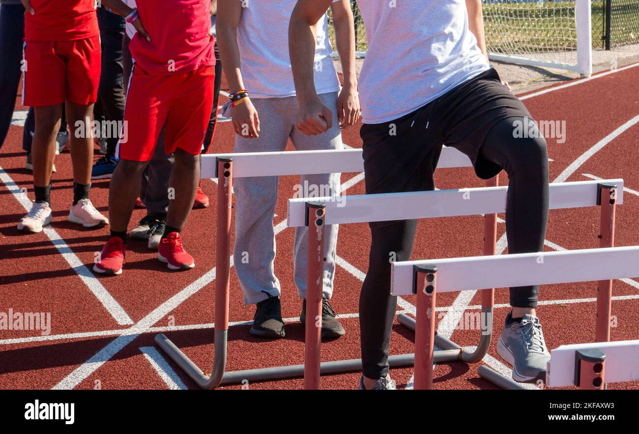 A high school blys track team walking over track hurdles during their ...