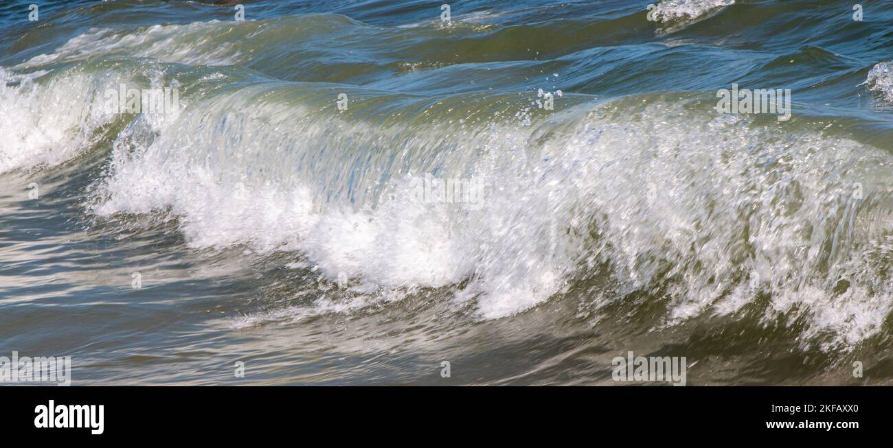Horizontal view of small Atlantic Ocean waves rolling on the shoreline ...
