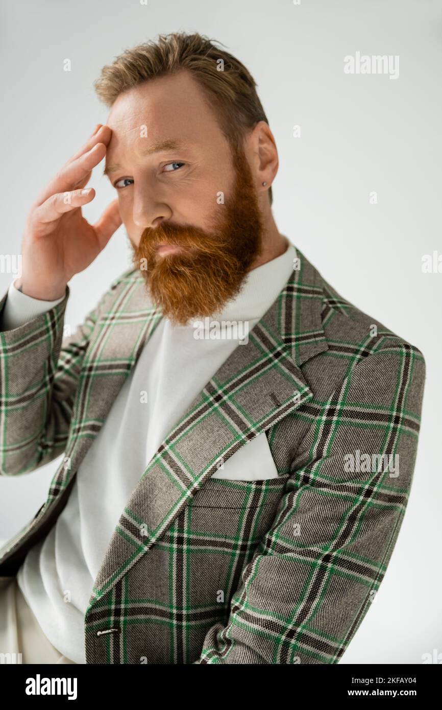 Trendy man in checkered jacket looking at camera while touching ...