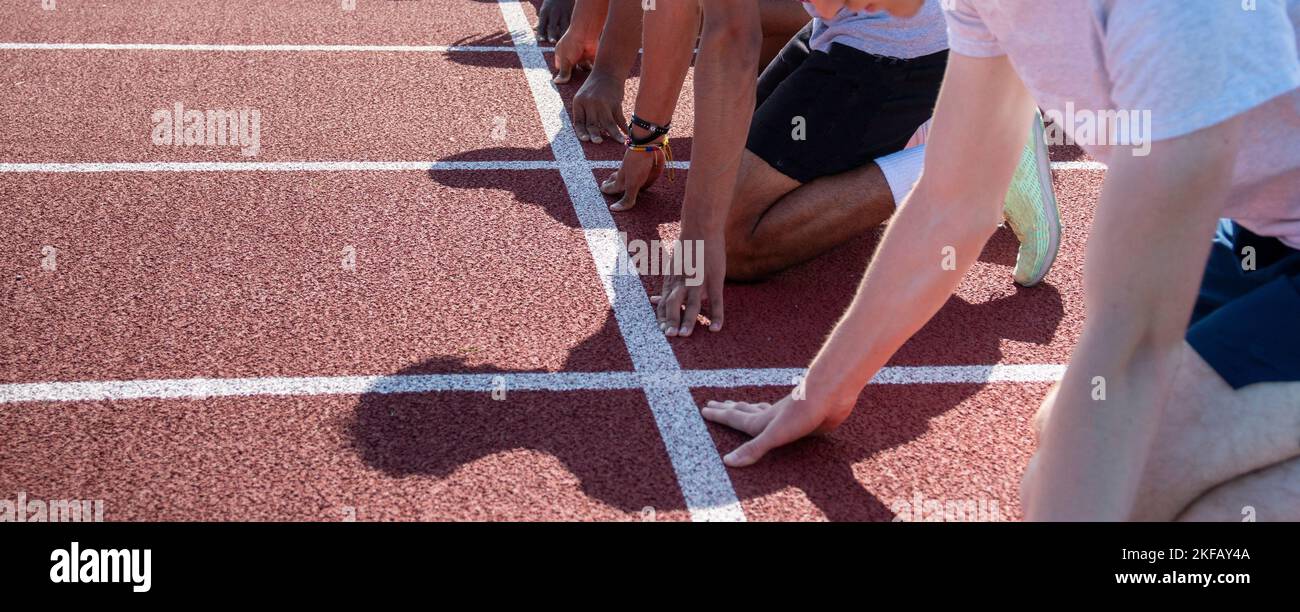 Side view of high school boys in lanes on a track ready to sprint ...