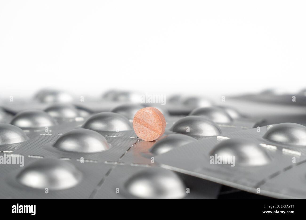 Pink pill on the background of packed pills. medicine in tablets. Close ...