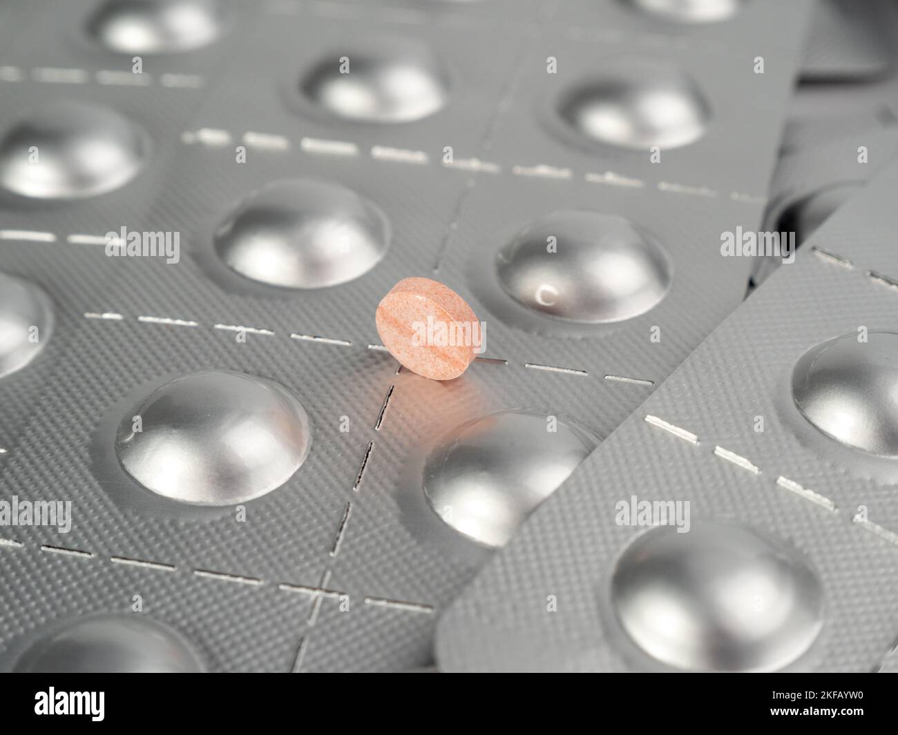 Pink pill on the background of packed pills. medicine in tablets. Close ...