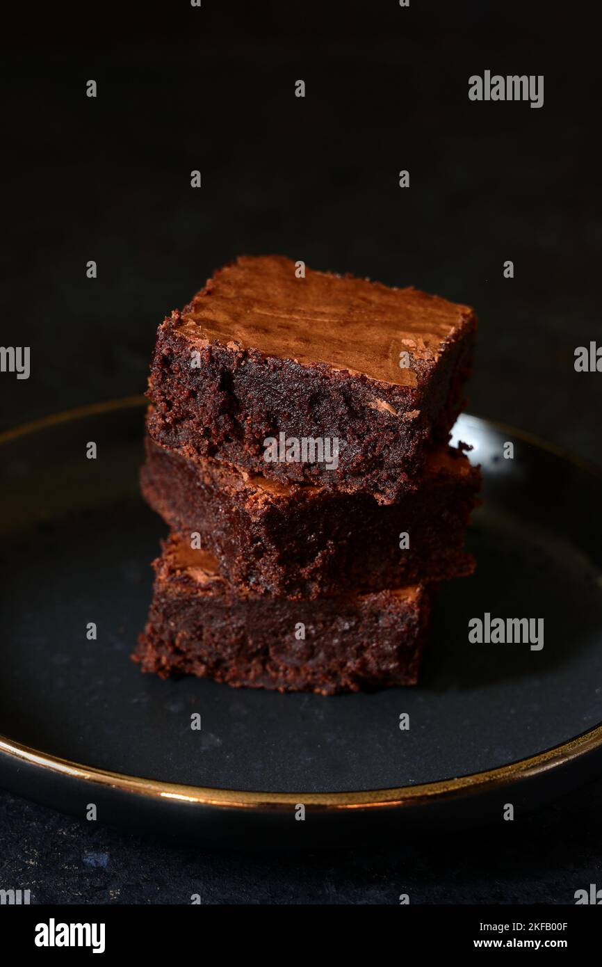 A stack of home baked rich indulgent chocolate brownies on a gold ...