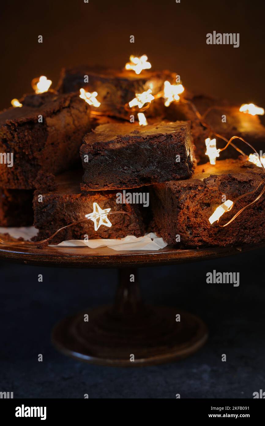 A stack of home baked rich chocolate brownies on a vintage wooden cake ...