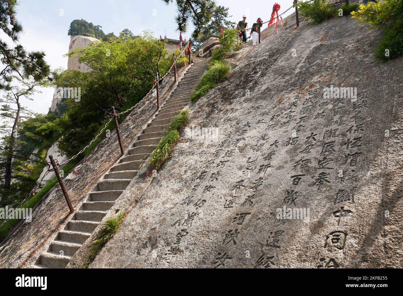 Visitor / tourist climbs steep steps cut into a stone rock face on ...