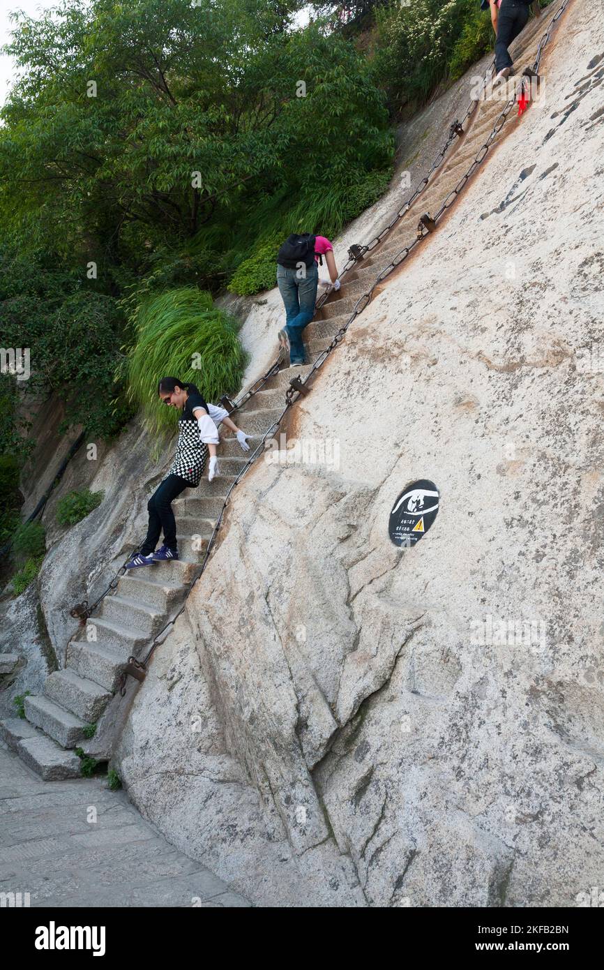 Visitor / tourist climbs steep steps cut into a stone rock face on ...
