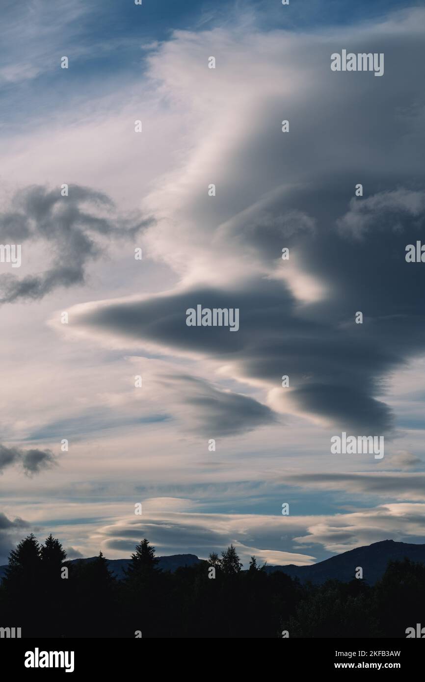 A vertical shot of white clouds forming a human's face with a big nose ...