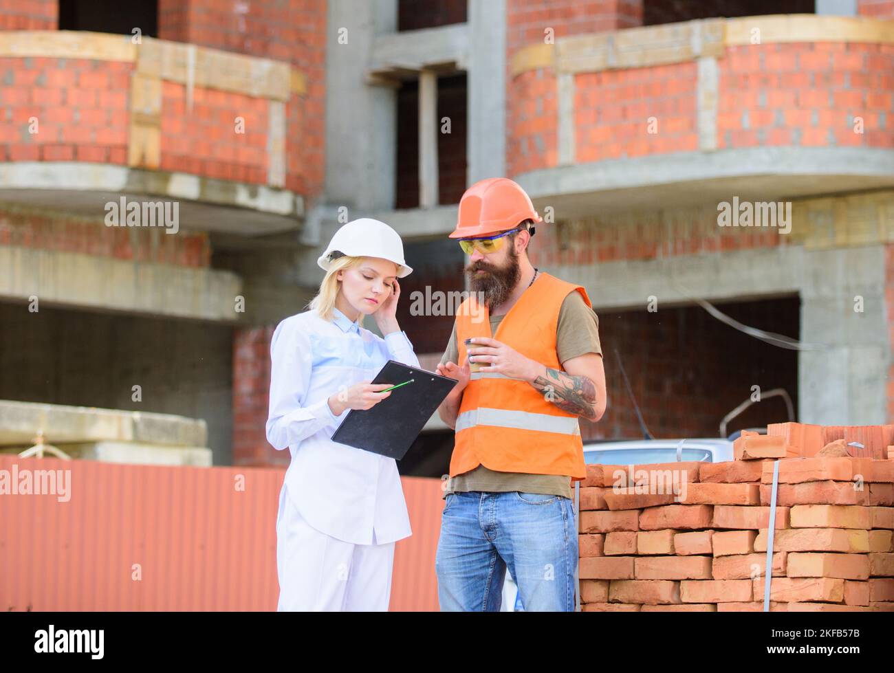 Discussing plan. Woman engineer and builder communicate at construction ...