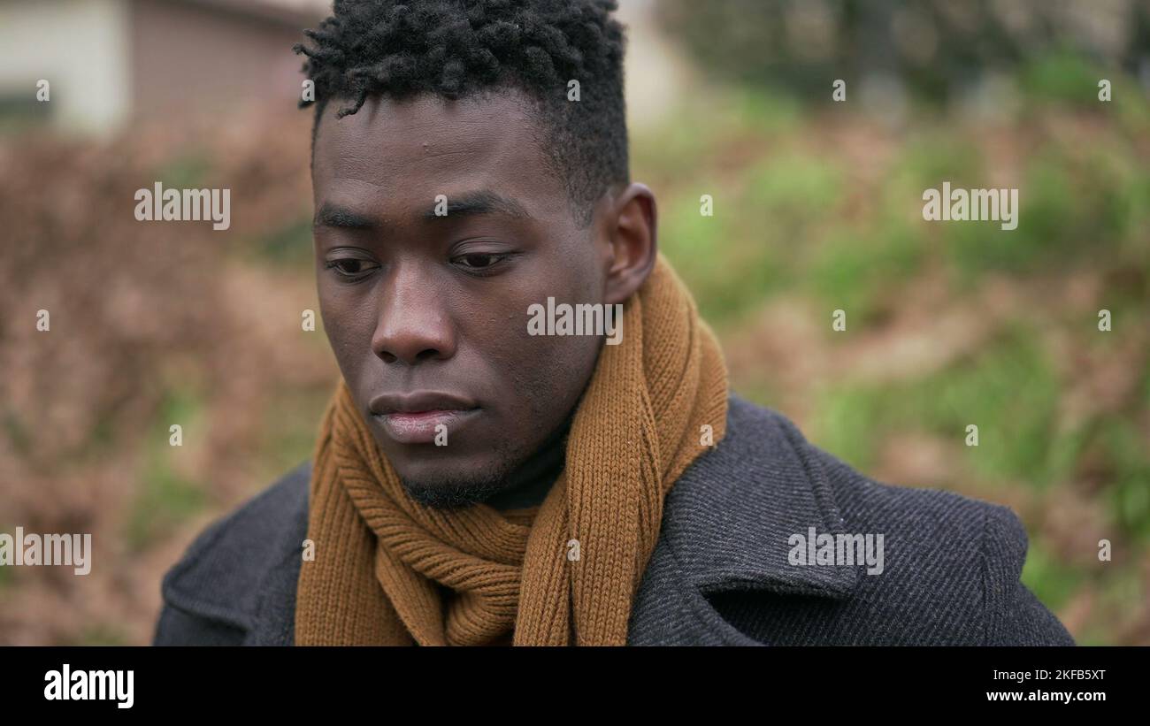 Contemplative young black man standing outside in nature park Stock ...