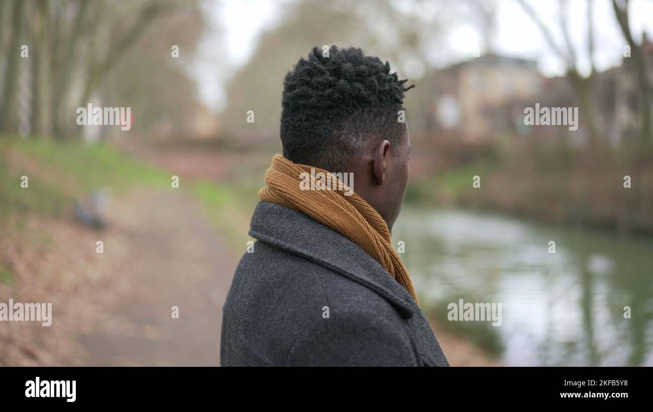 Contemplative young black man standing outside in nature park Stock ...