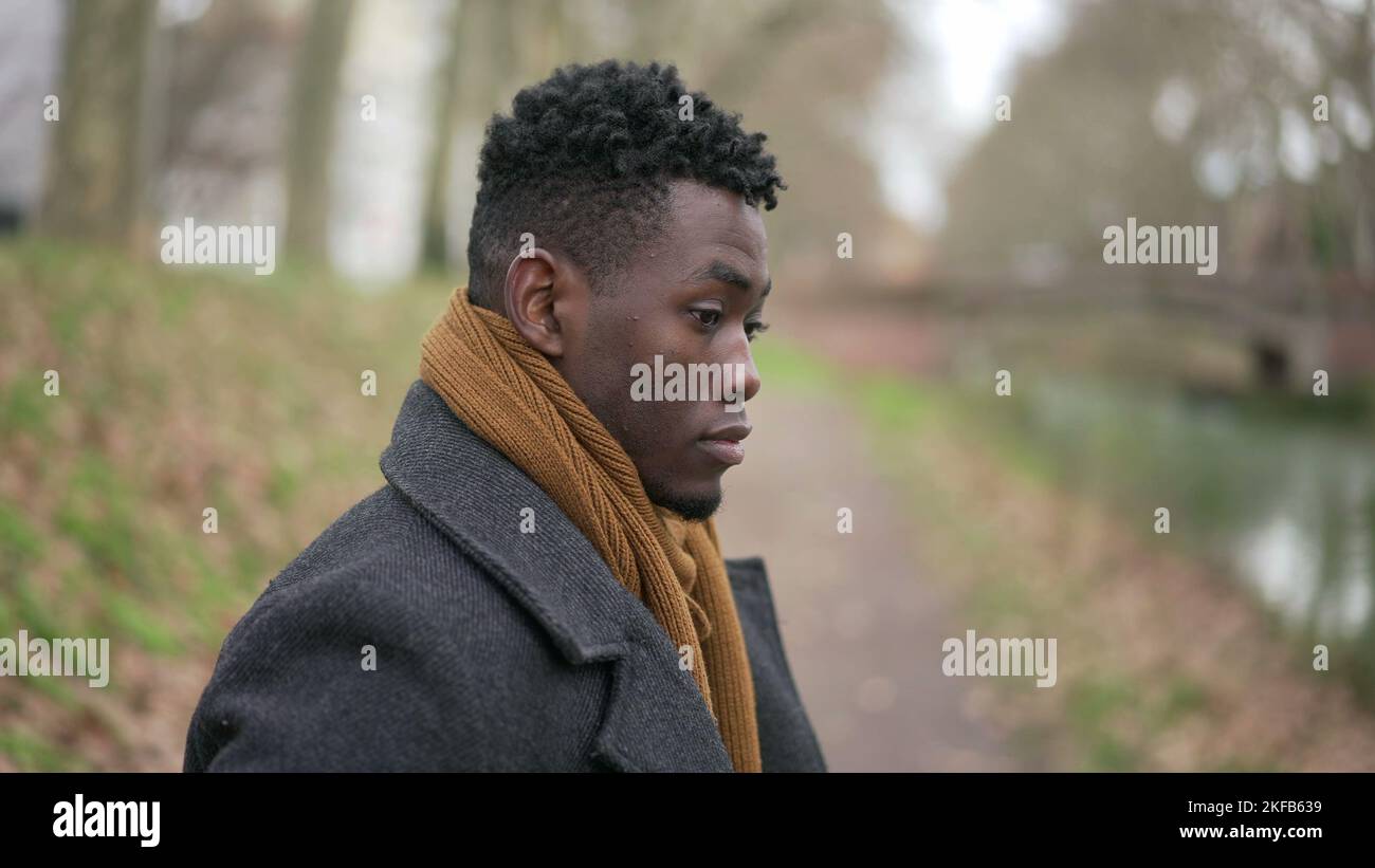 Contemplative young black man standing outside in nature park Stock ...