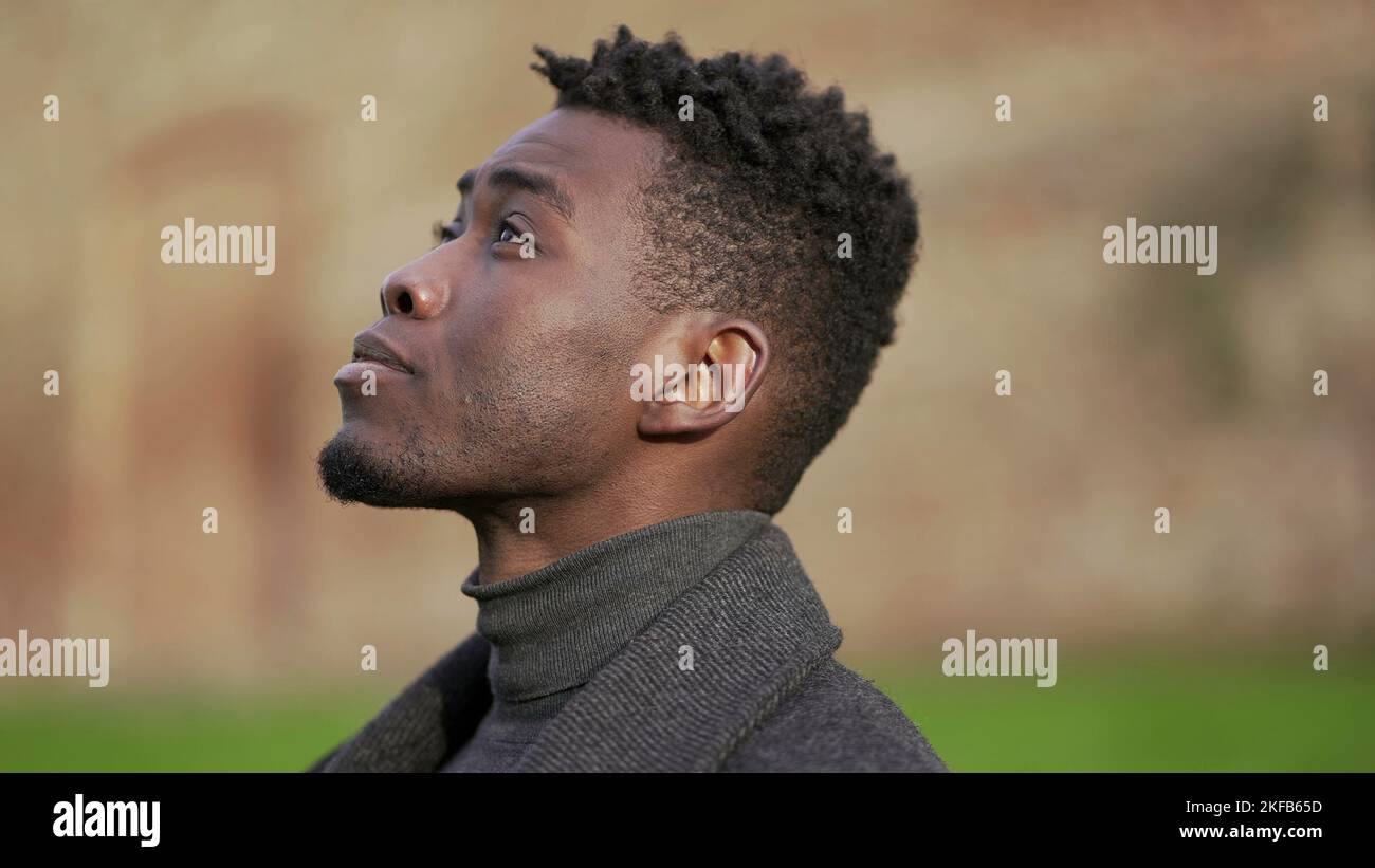 Contemplative young African black man standing looking at sky with HOPE ...
