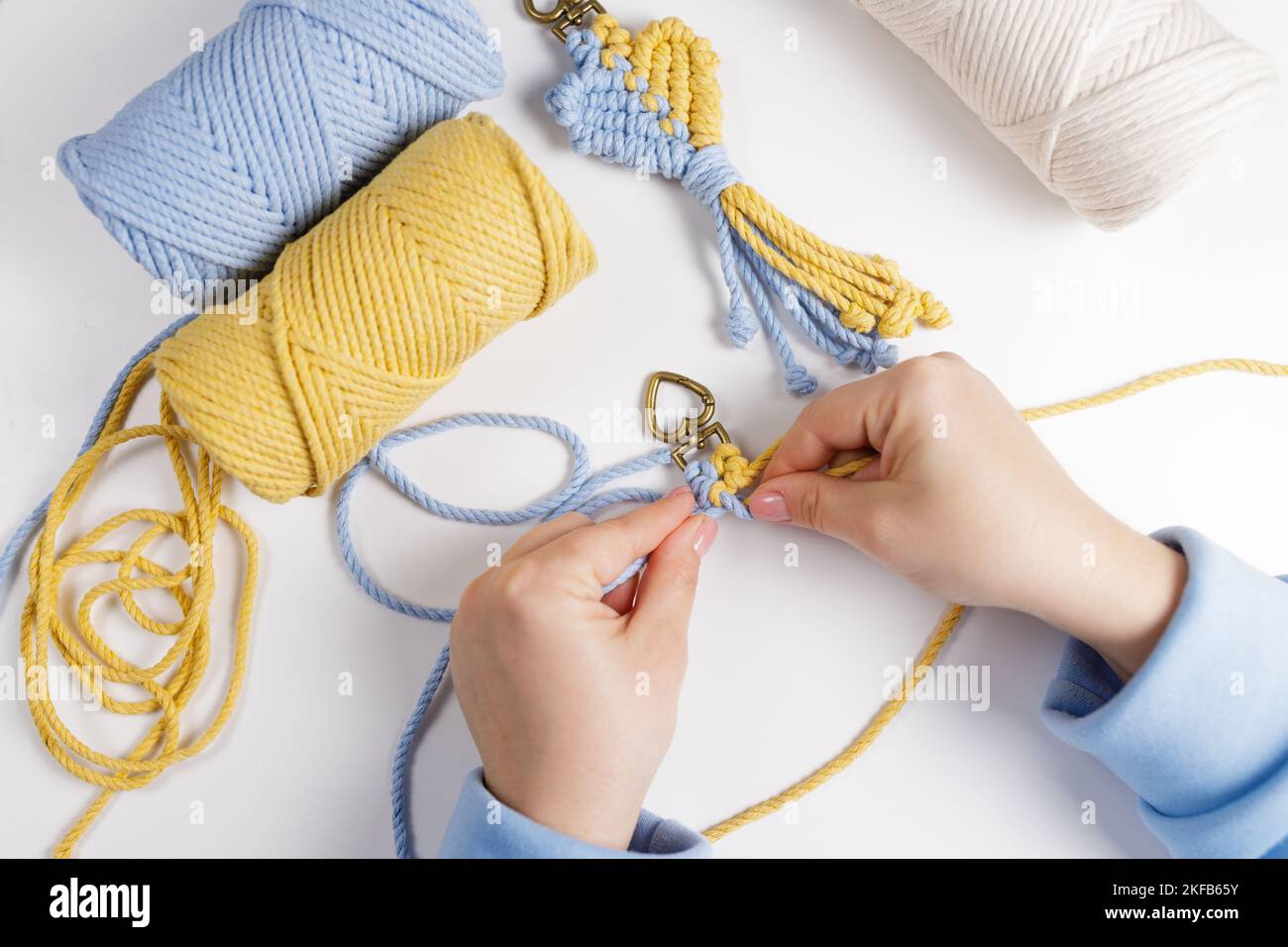Hands of young woman working on macrame decor with blue and yellow ...
