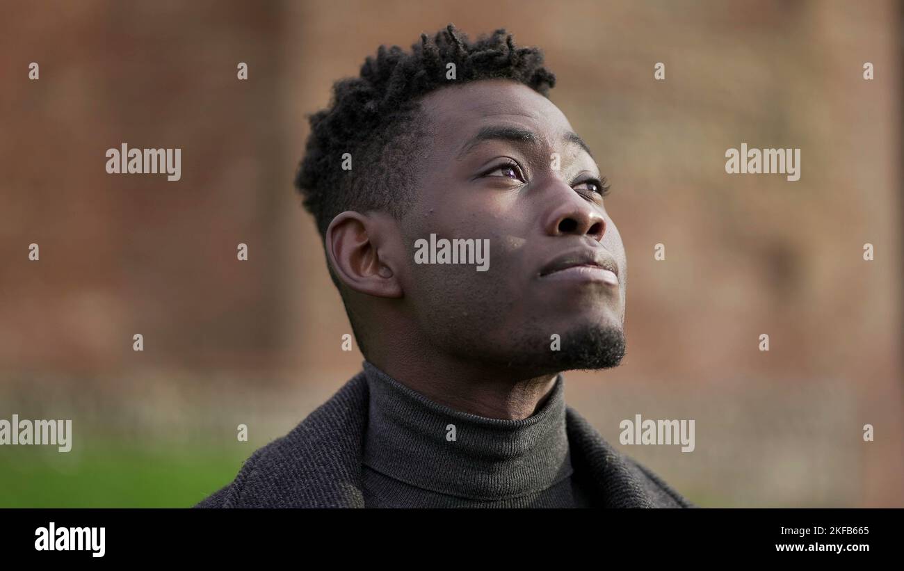 Contemplative young African black man standing looking at sky with HOPE ...