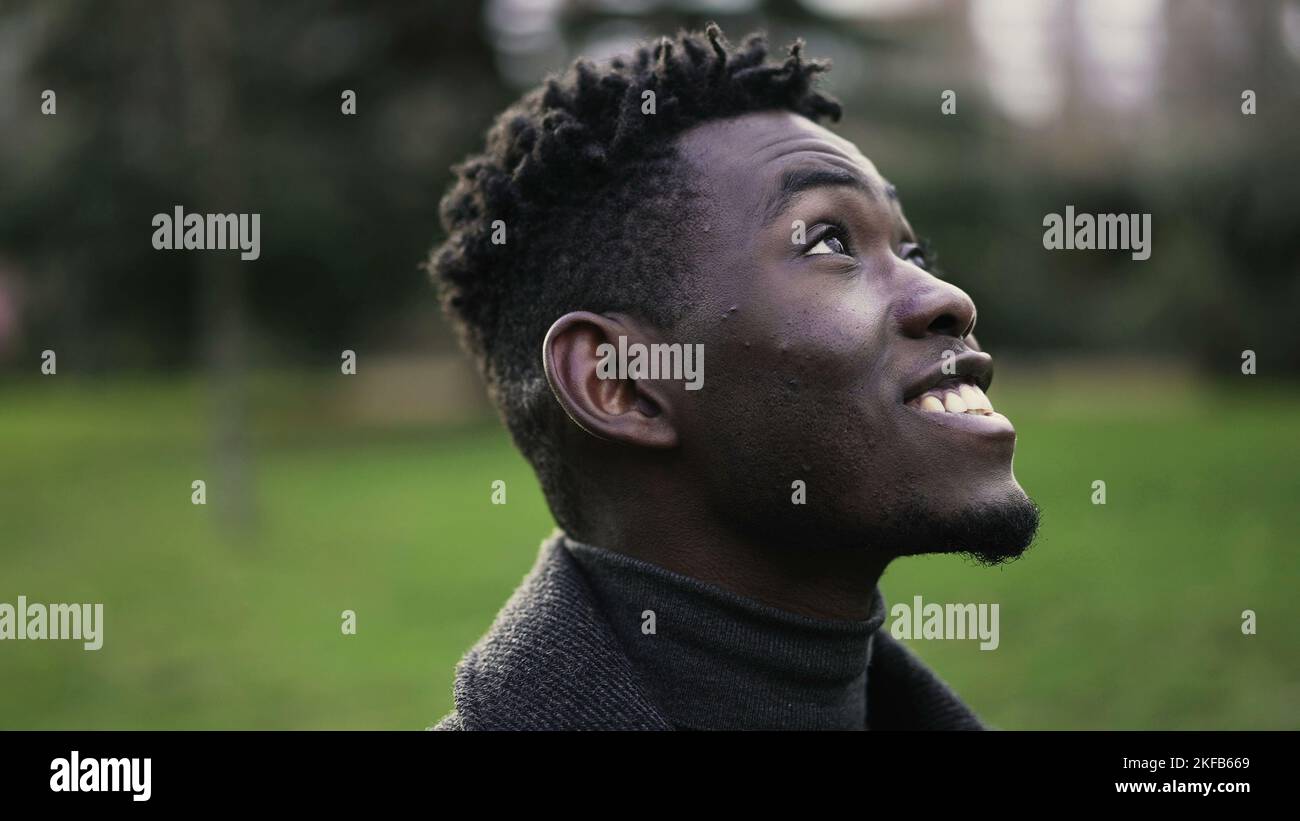 Contemplative young African black man standing looking at sky with HOPE ...