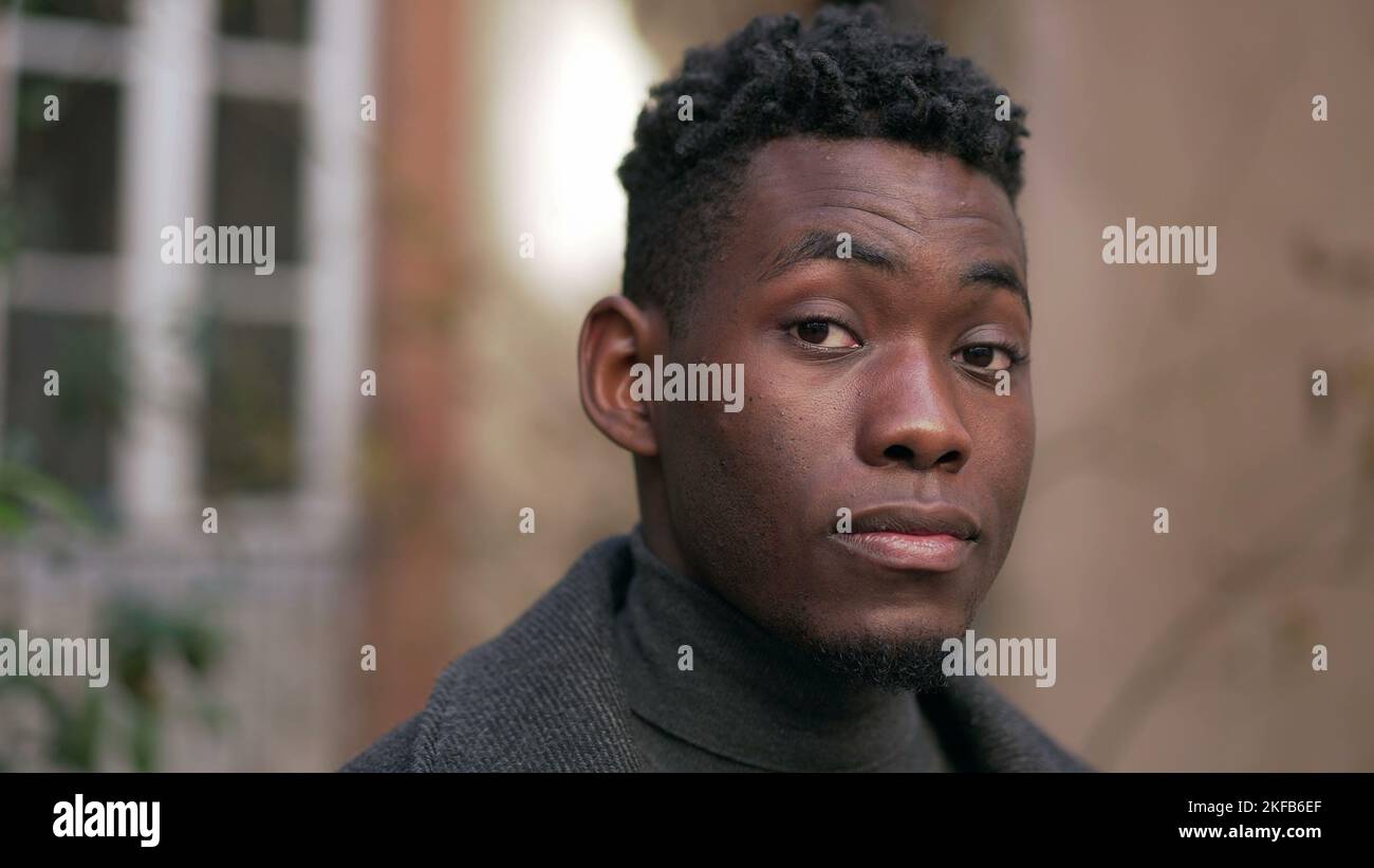 Confident young black man standing outside staring camera portrait face ...