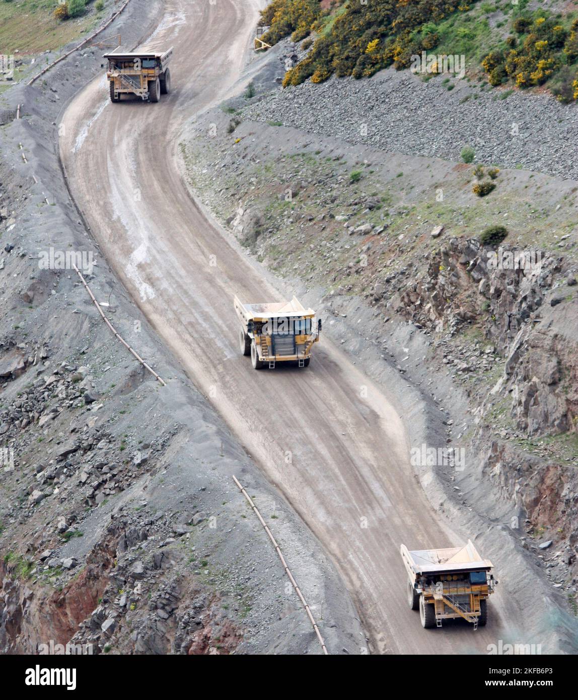 Three Large Lorry Trucks Driving Down a Quarry Incline Stock Photo - Alamy