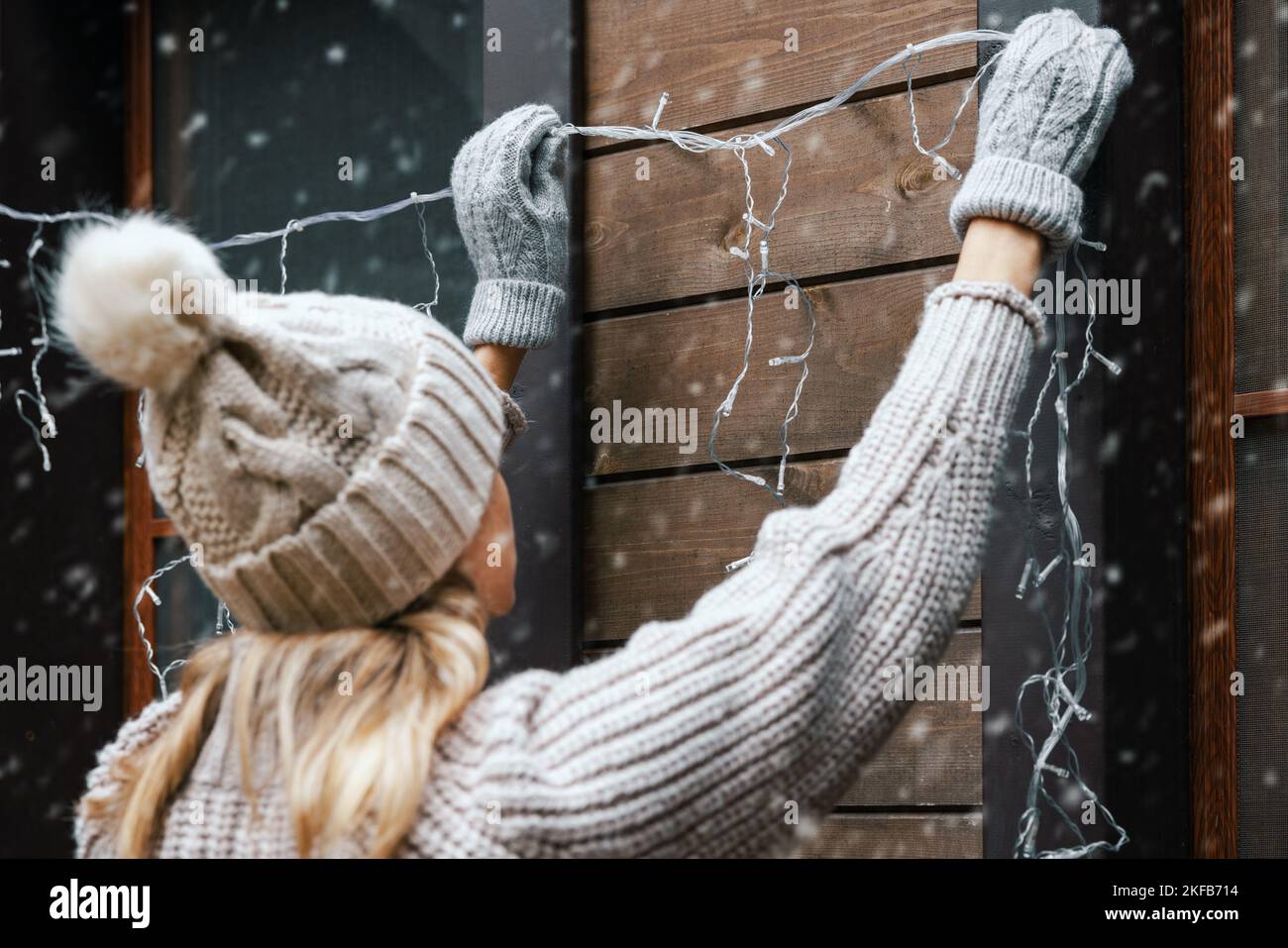 christmas home decorations. woman install electric string lights on ...