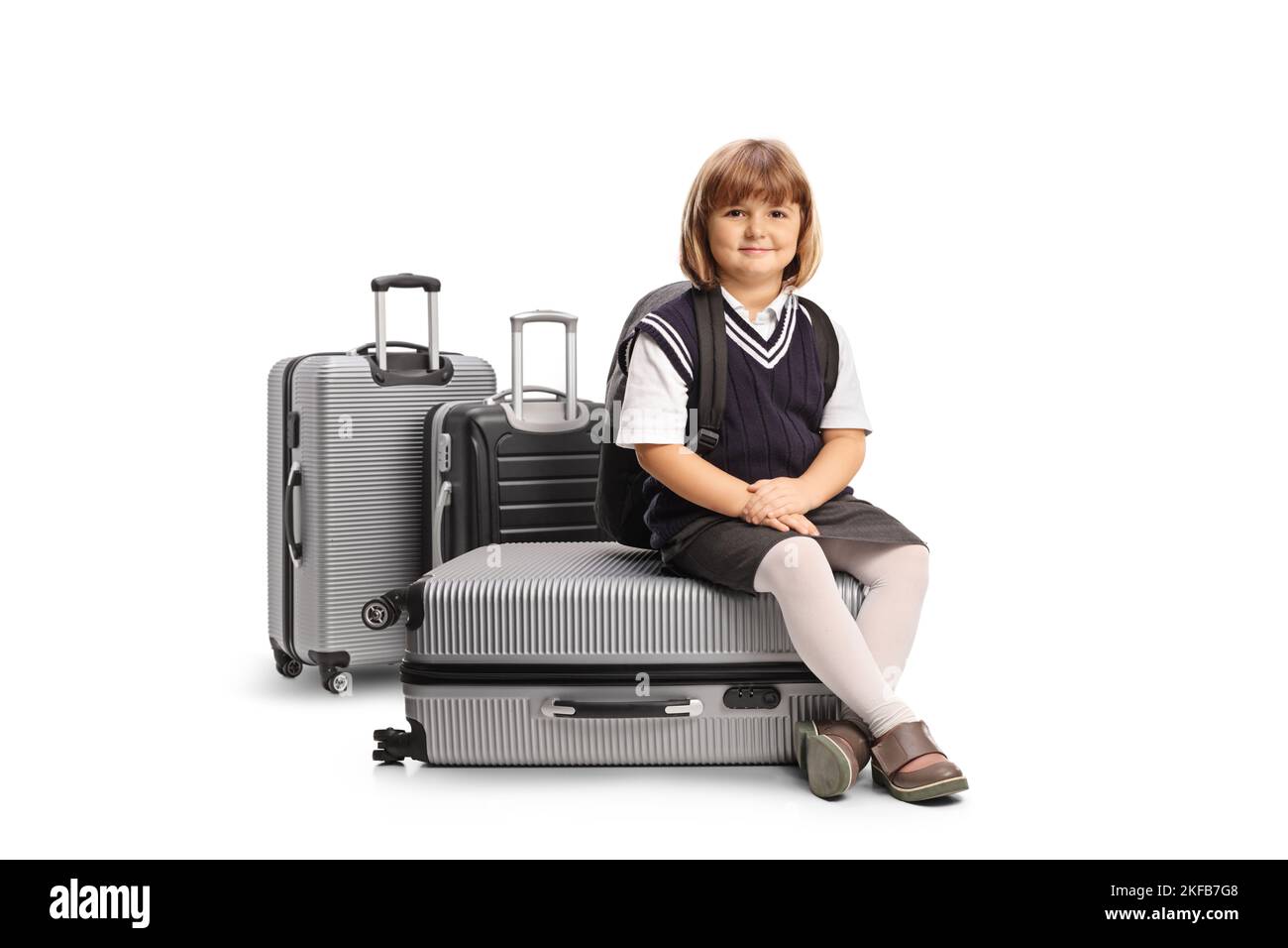 Little girl sitting on a suitcase and smiling isolated on white ...