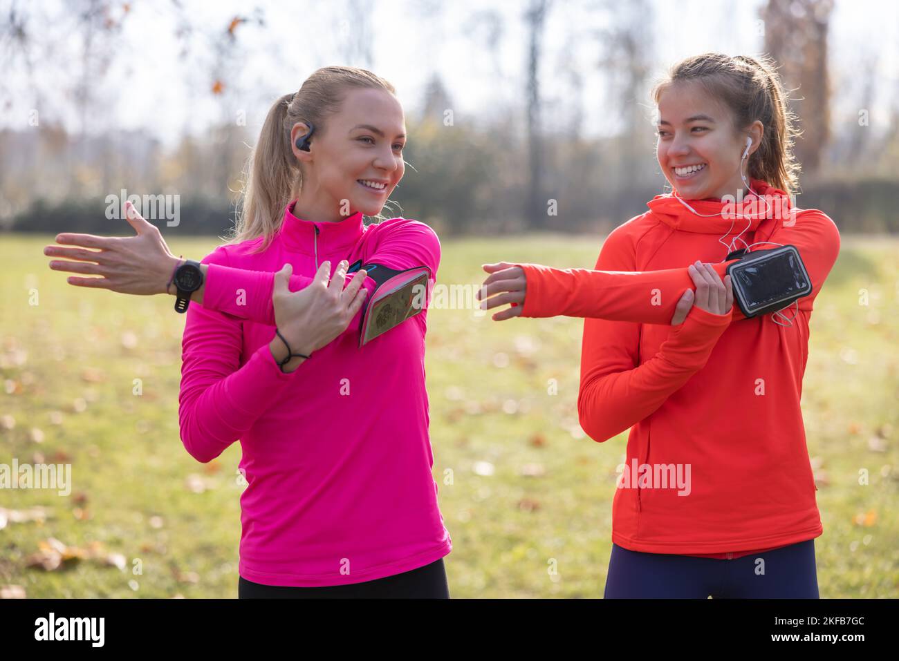Two female athletes are exercising before jogging, doing upper body ...