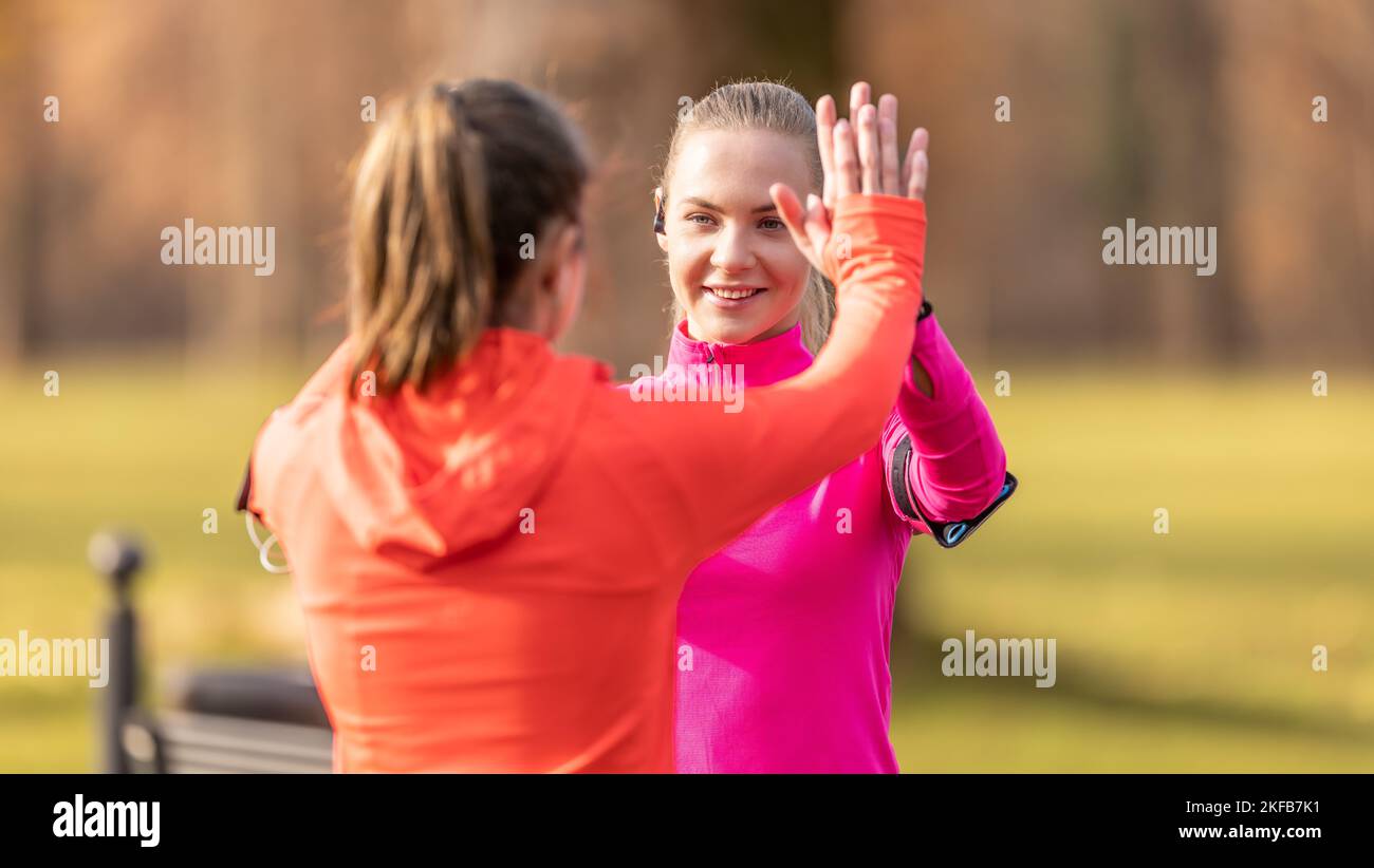 Two female athlete friends support each other and give high-five after ...