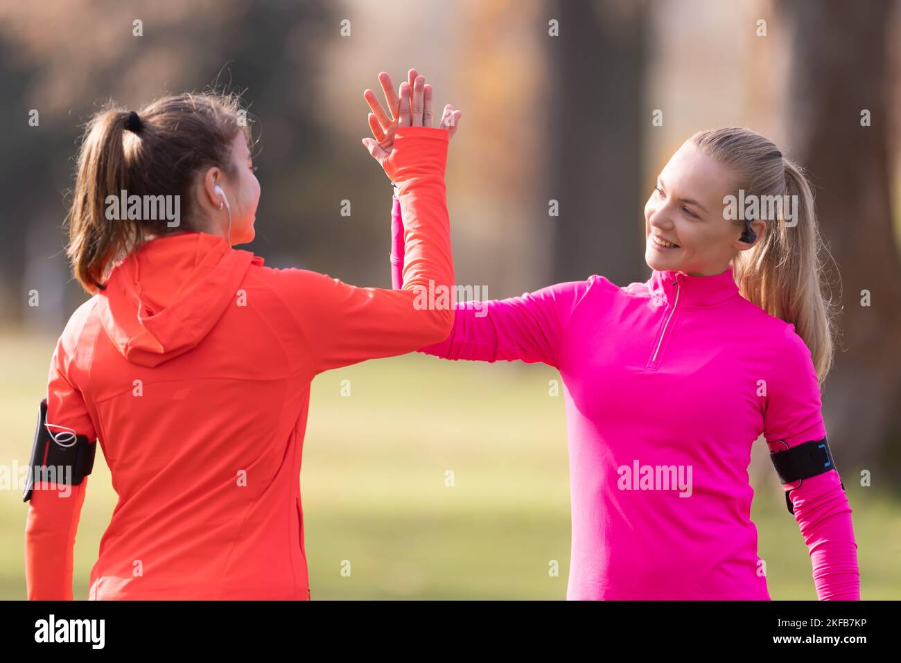 Two female athlete friends support each other and give high-five after ...