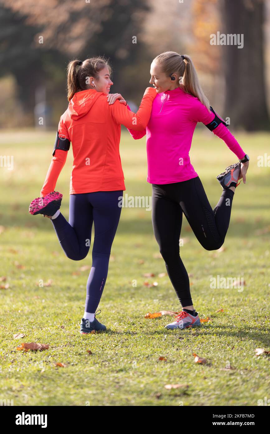 Sporty female athletes are warming up before jogging, doing lower body ...