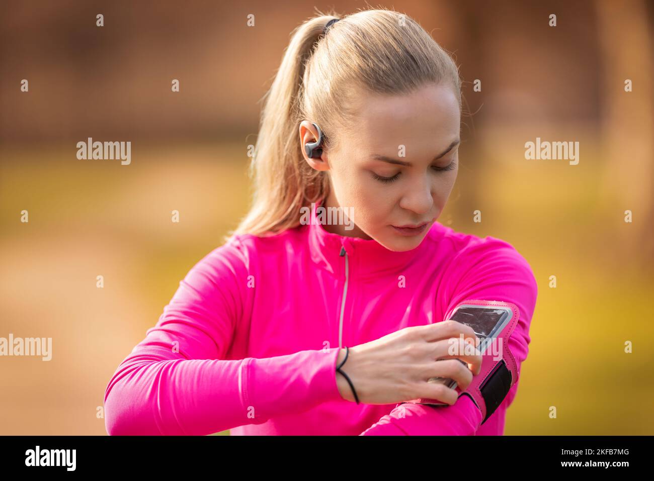 A beautiful young athlete with a mobile phone on her shoulder starts ...