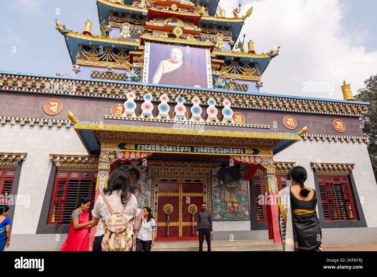 Visitors take a photo of the Temple with a photo of His Holiness Penor ...
