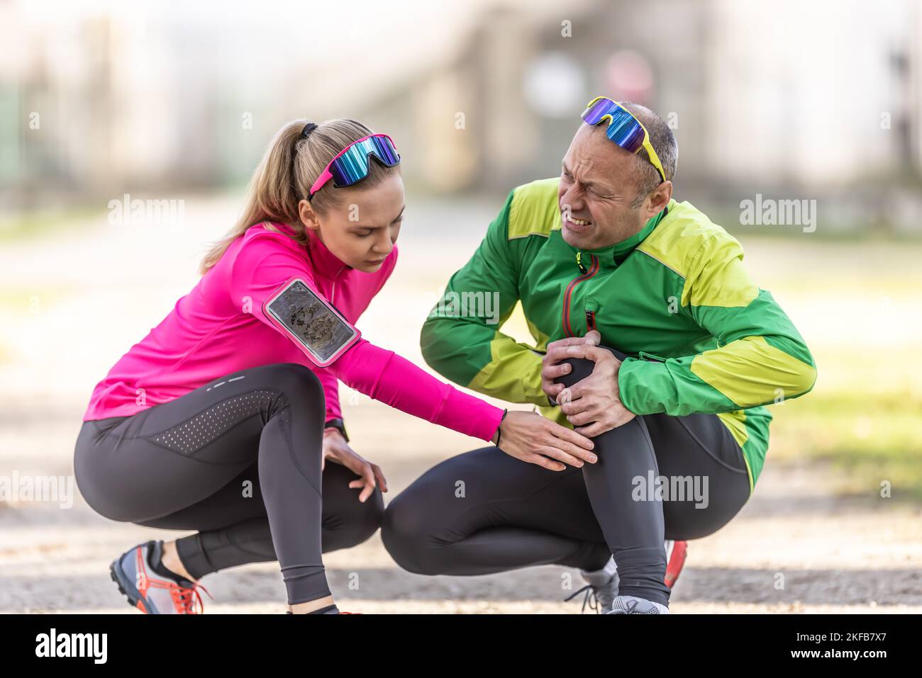 A mature man's knee pain after running is given first aid by a young ...