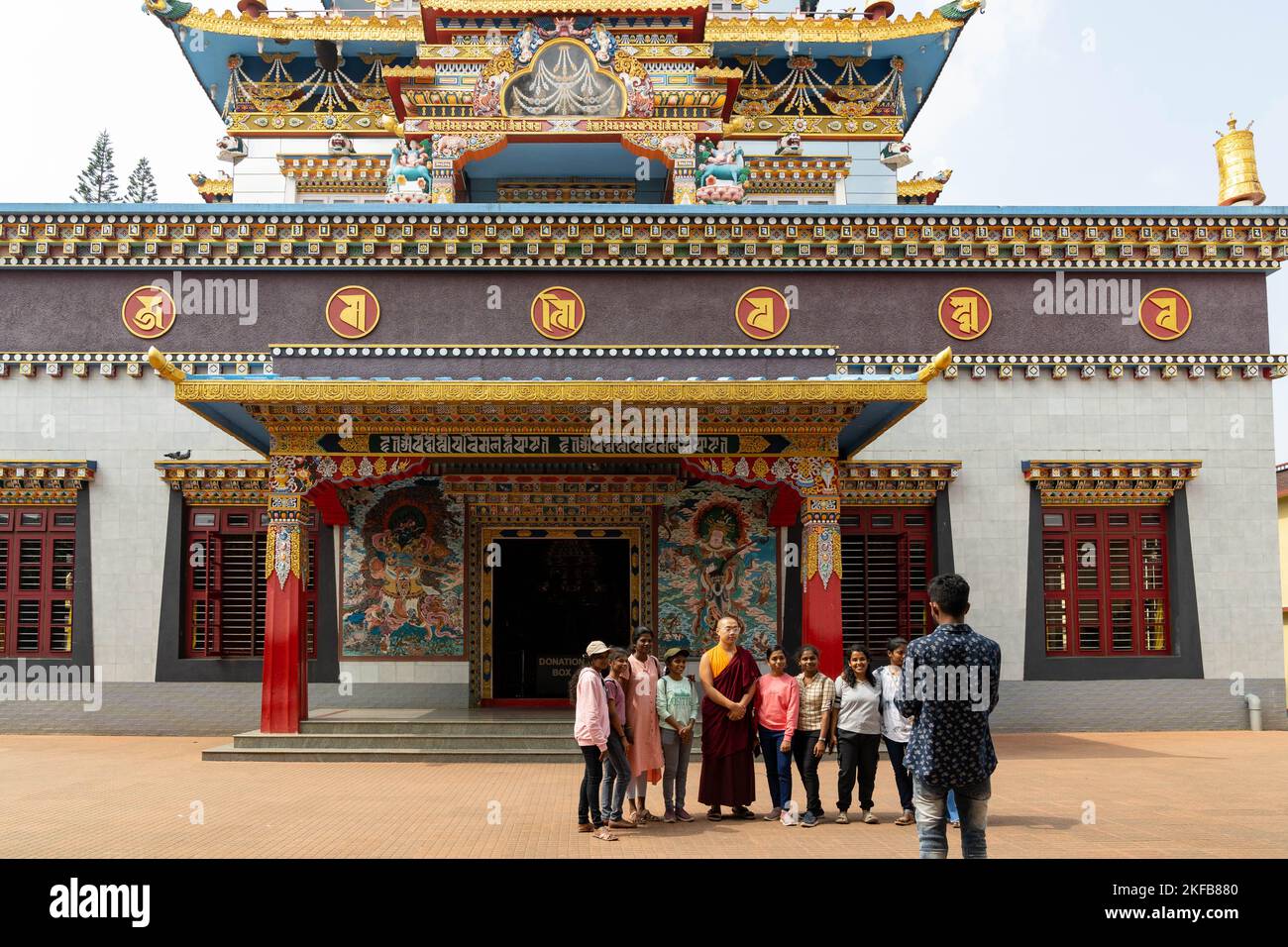 A group of visitors take a photo with a Buddhist monk in front of a ...