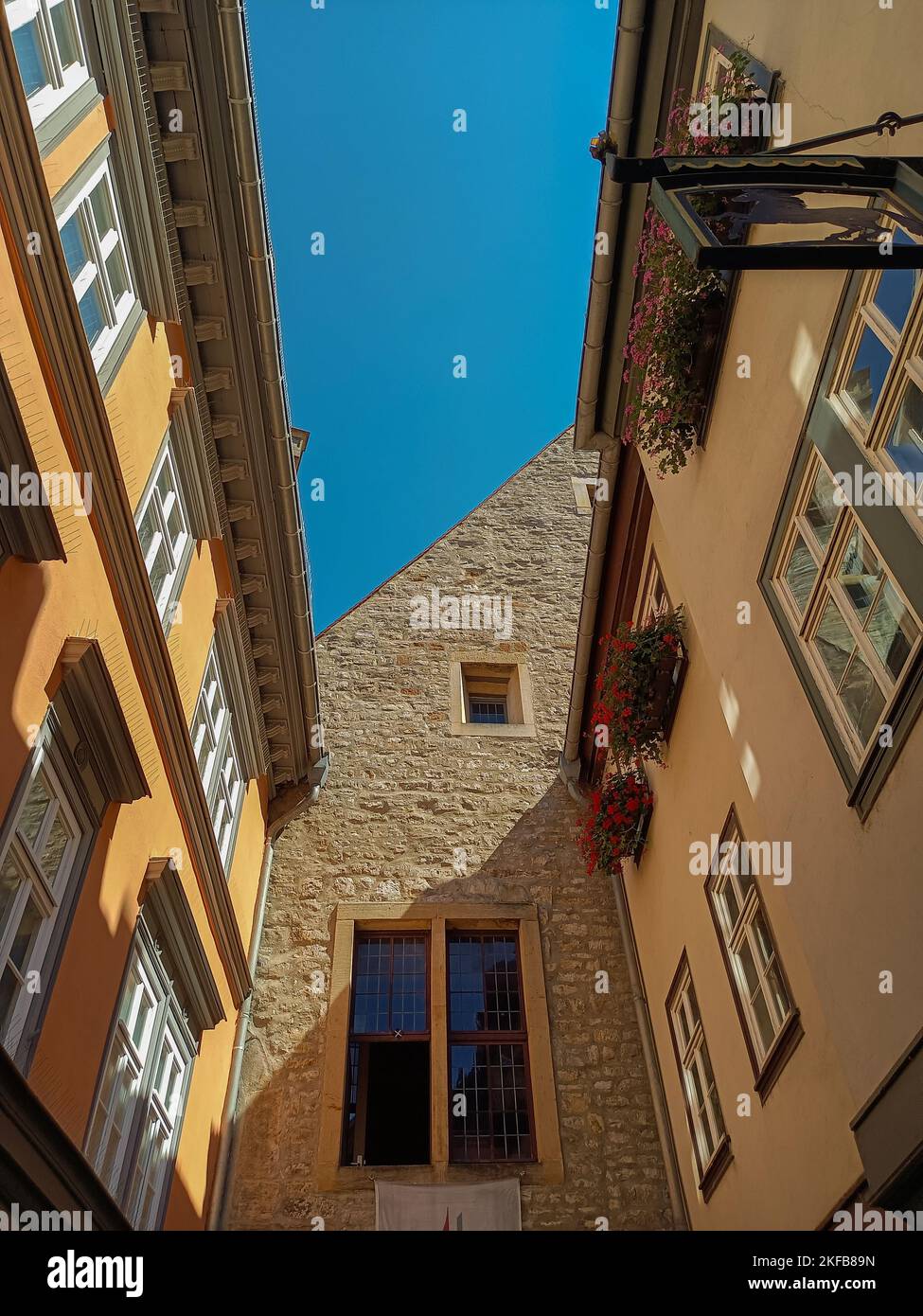 Old buildings in yellow on both sides with a brig wall in the back ...