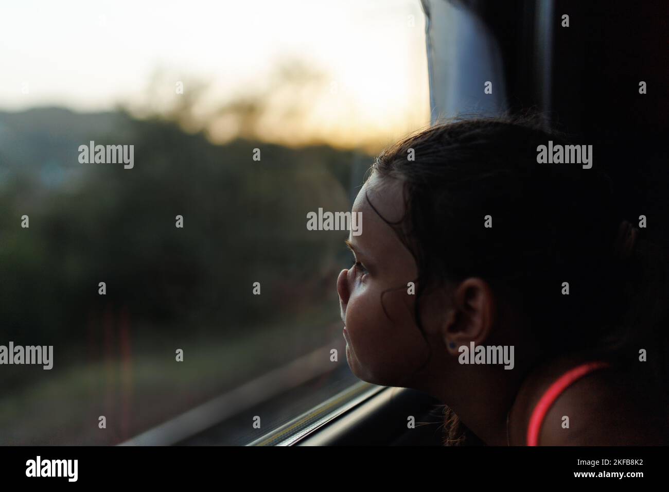 Thoughtful, funny, adorable little girl nuzzle, nestle at window glass ...
