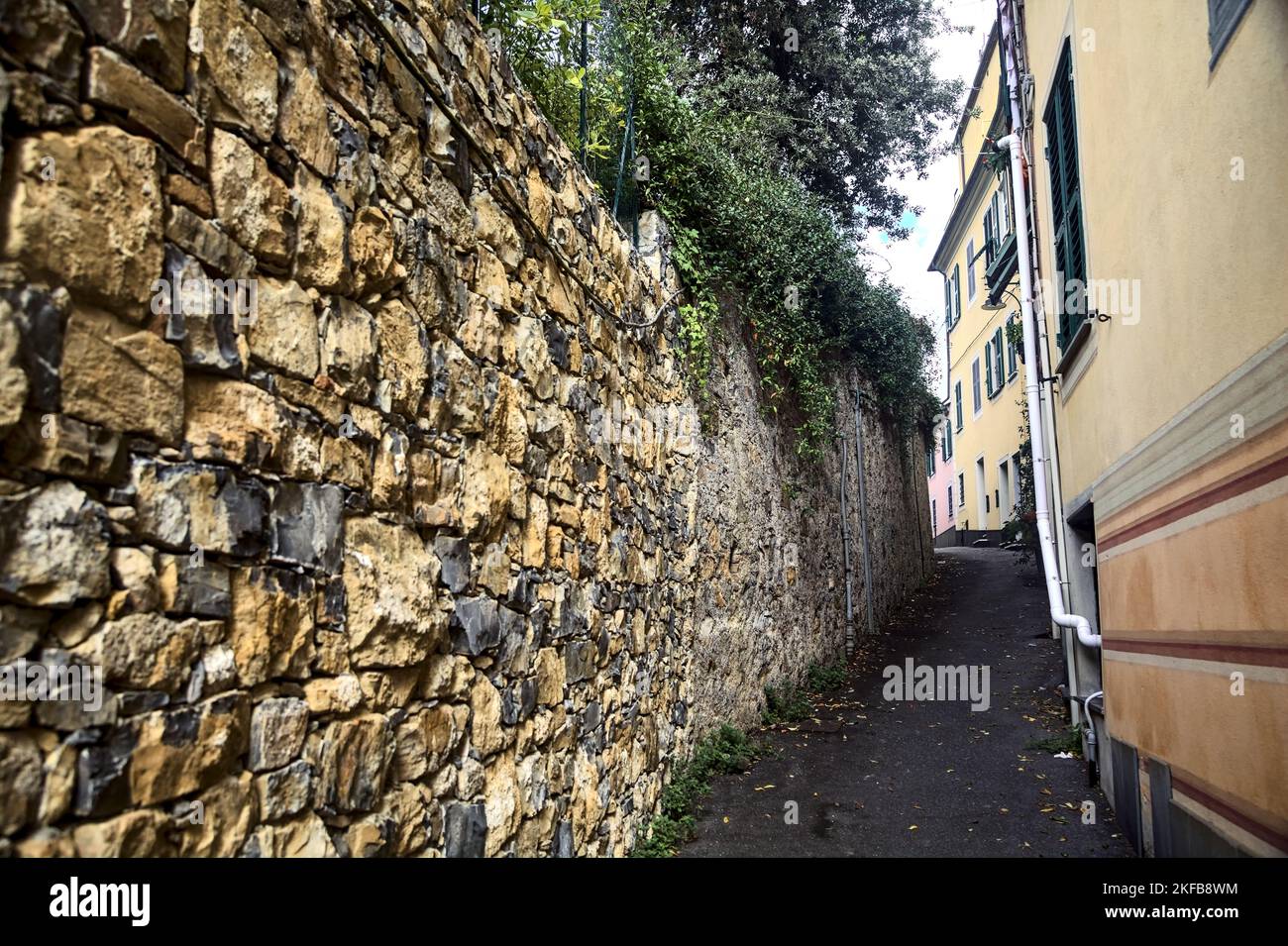 Uphill alley between a stone wall and a building Stock Photo - Alamy