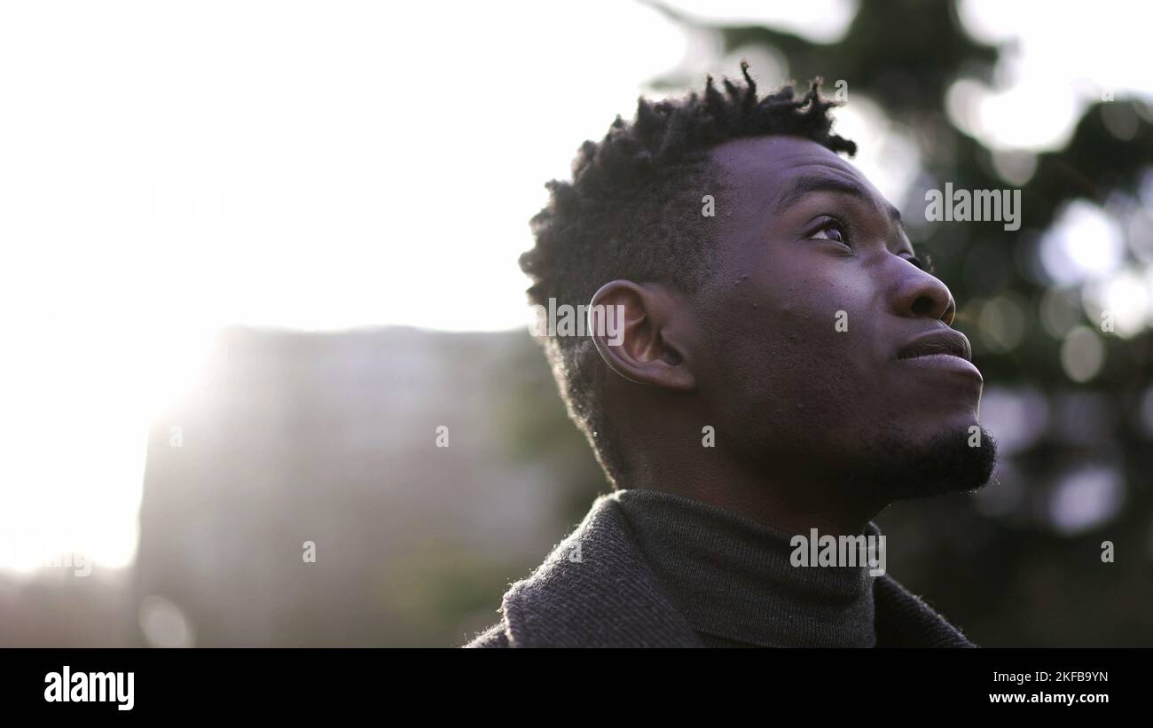 Contemplative young African black man standing looking at sky with HOPE ...